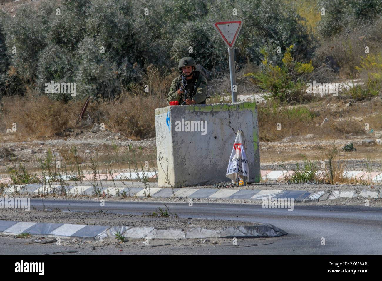 An Israeli soldier stands on guard against Palestinians while the ...