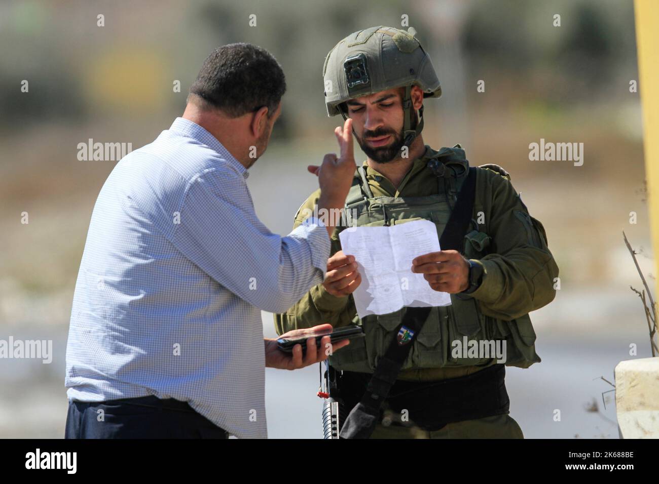 An Israeli soldier checks a Palestinian identities as the Jewish ...