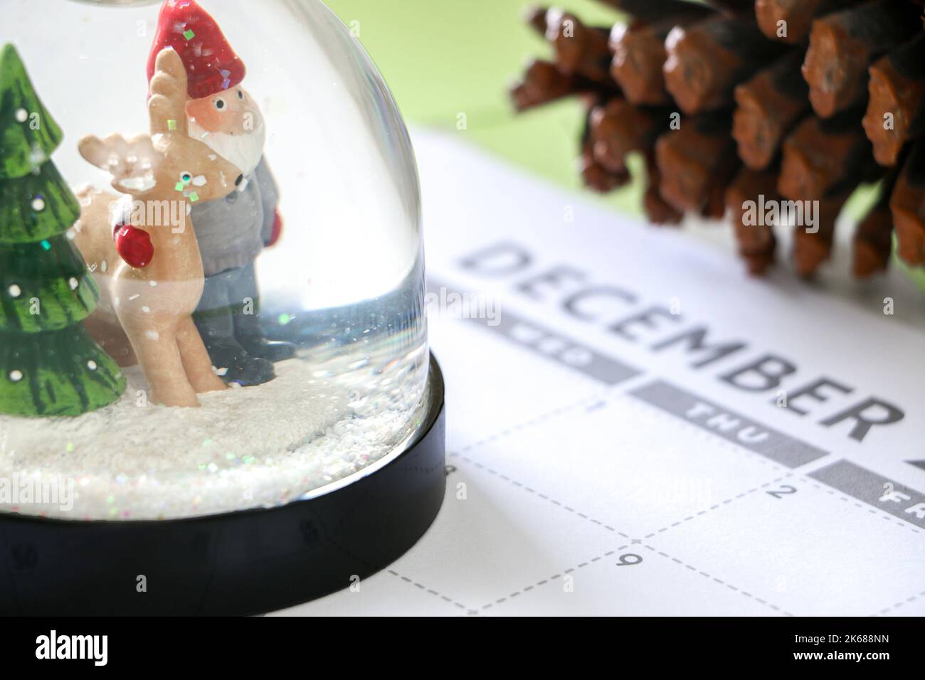 Christmas time, festive snow globe on December calendar with pine cone ...