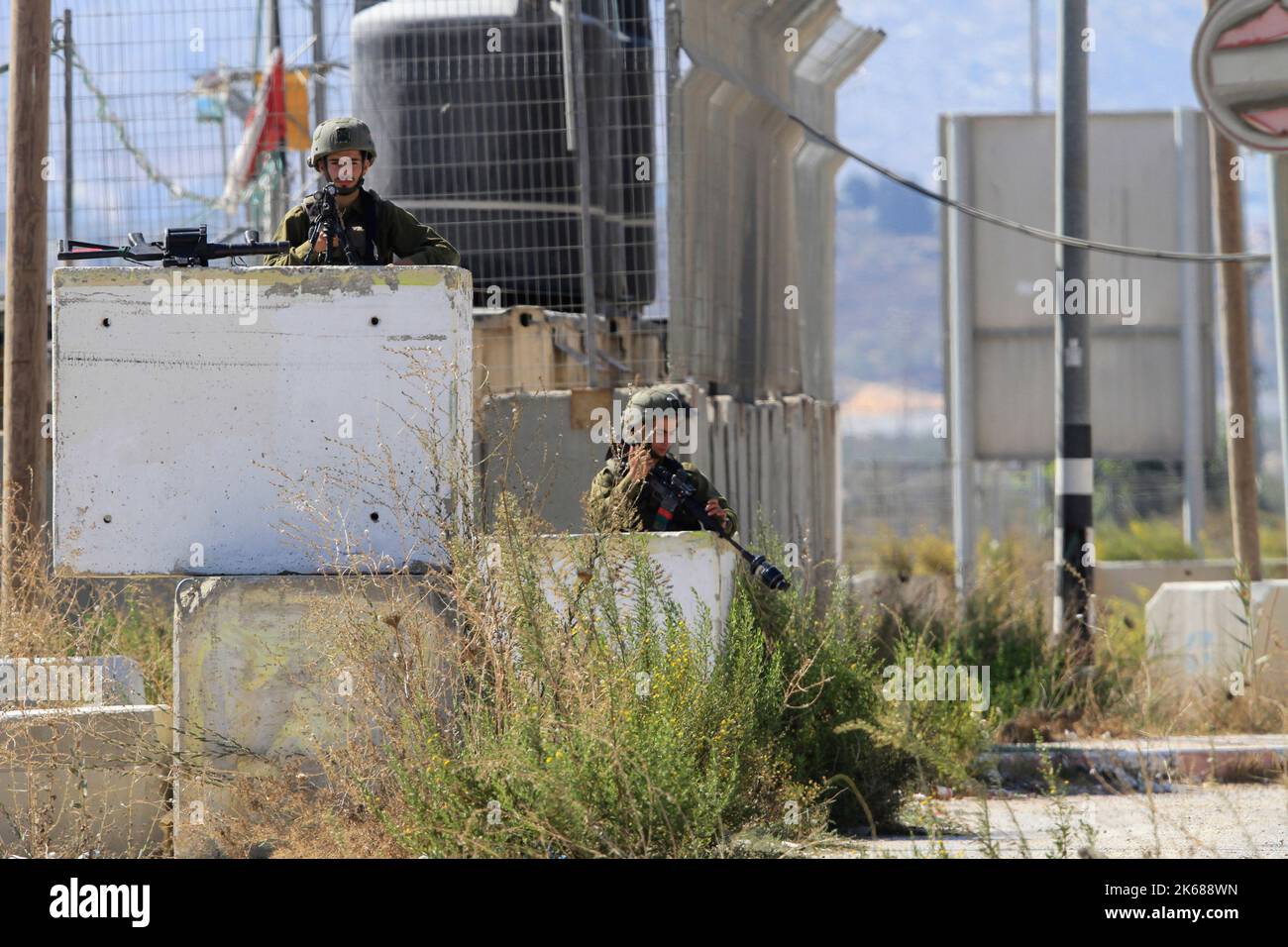 Israeli soldiers stand guard against Palestinians while the Jewish settlers block Hawara ...