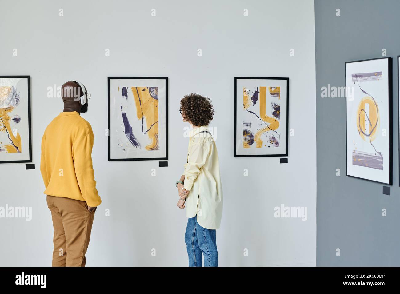 Young people examining modern art on the wall during exhibition at art ...