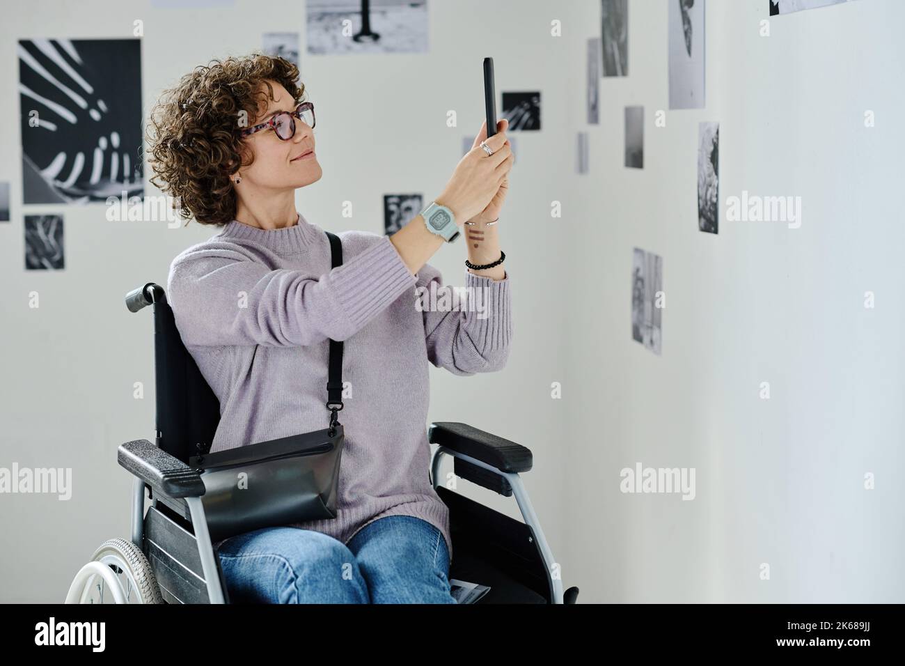 oung woman with disability photographing pictures on wall on her ...