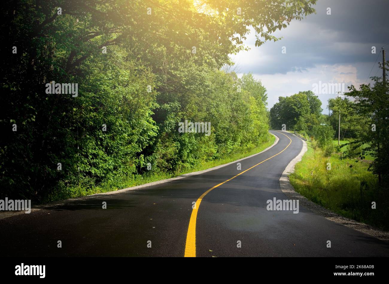 Rural Curved Road With Bright Yellow Line and Sun Rays Horizontal Stock ...