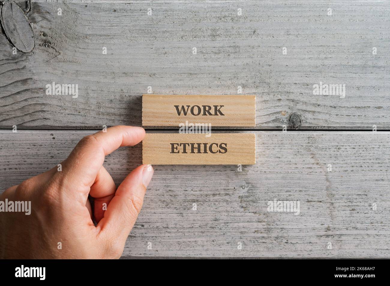 Male hand assembling a Work ethics sign written on two wooden blocks ...