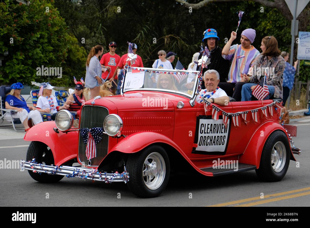 A caucasian couple driving in a red, open-top classic car participating ...