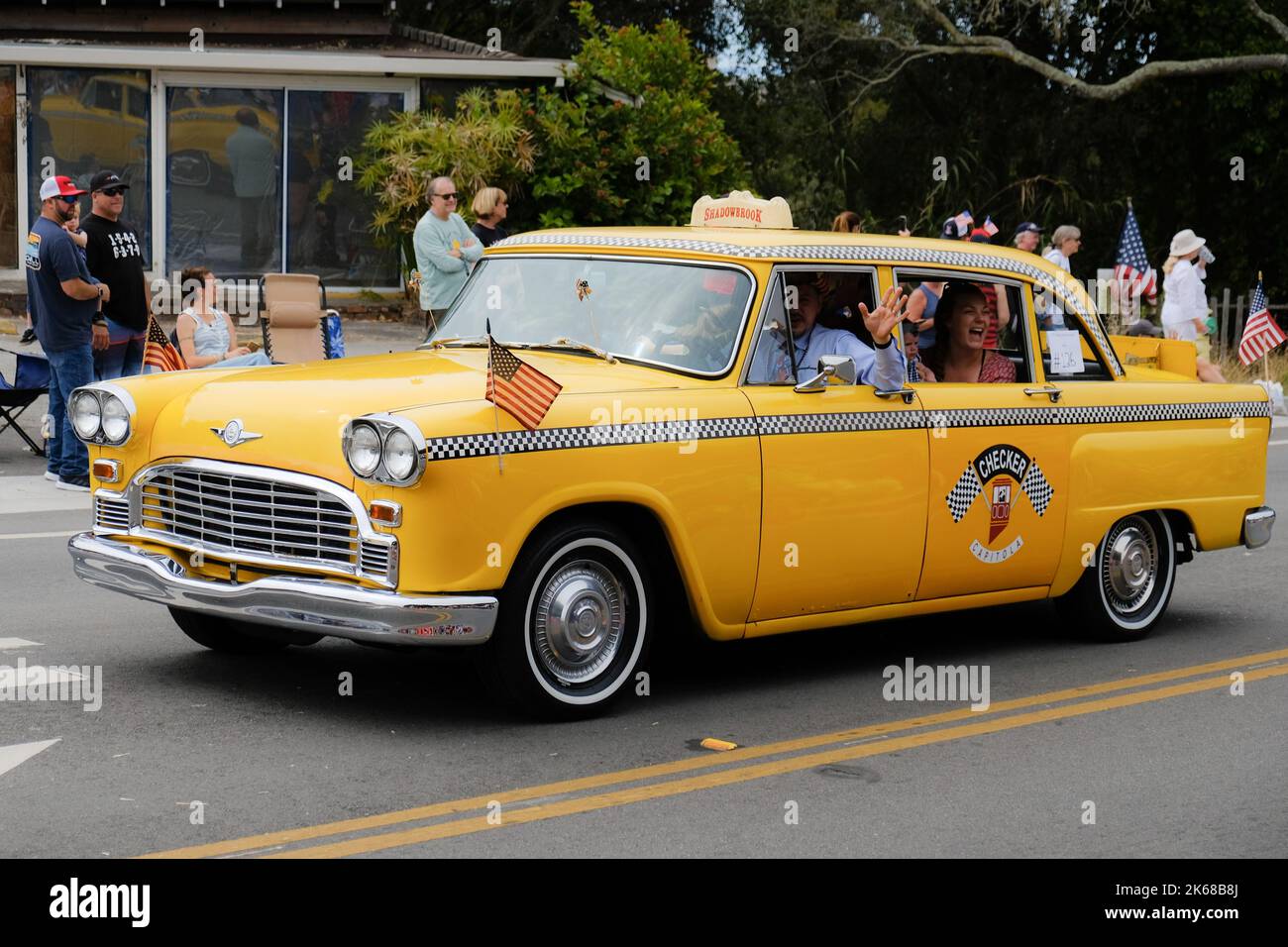 A yellow taxicab with a waving man and a laughing woman inside ...