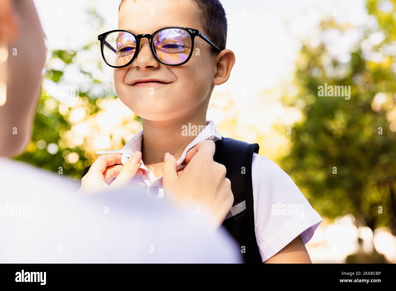 The mother arranges the child's shirt before leaving for school, the first day in primary class ...
