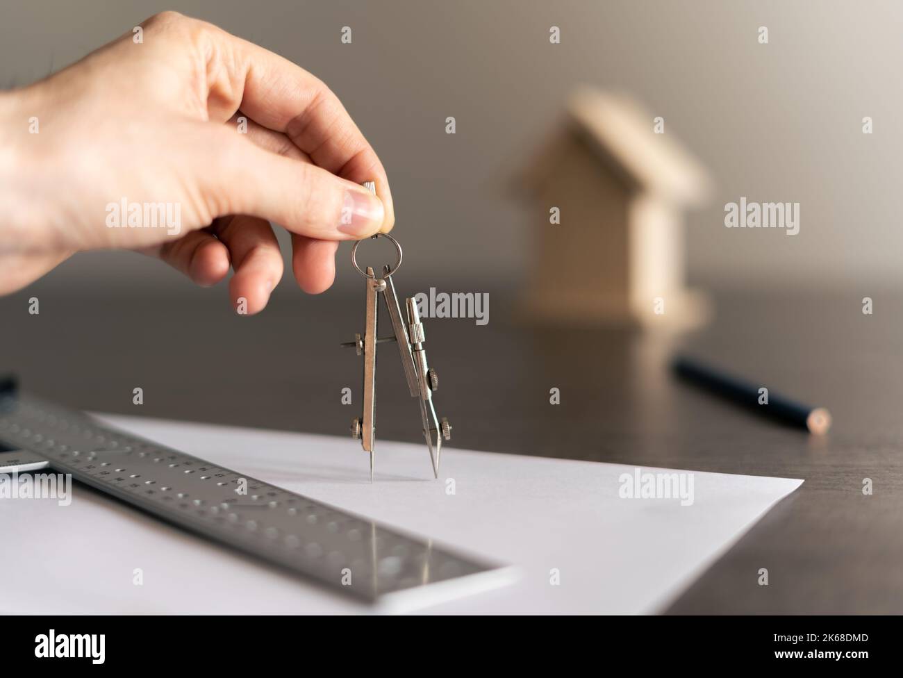 Architect drawing with the compass on a white paper the plans of a new ...