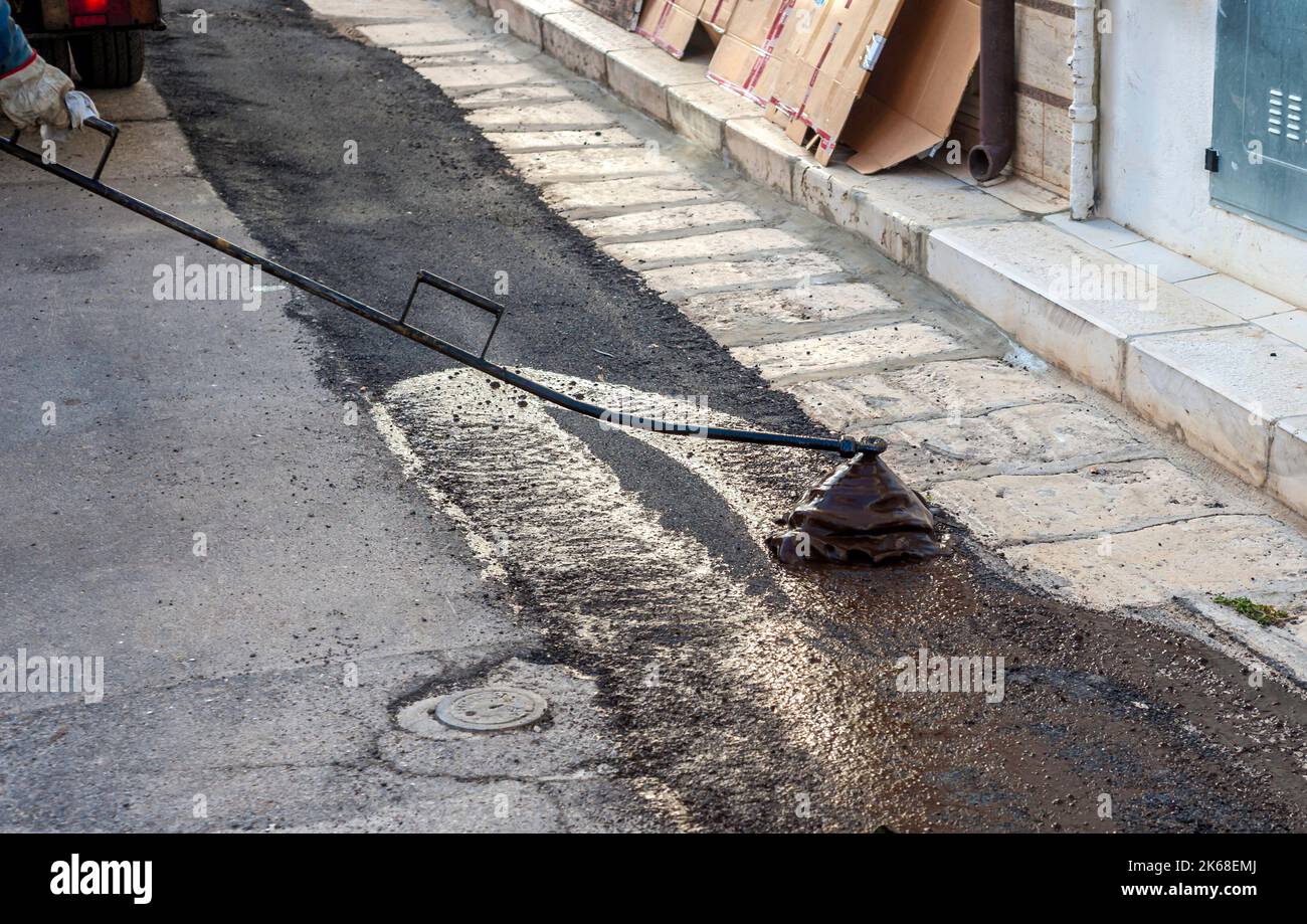 Road worker spraying bitumen emulsion with the hand spray lance before ...