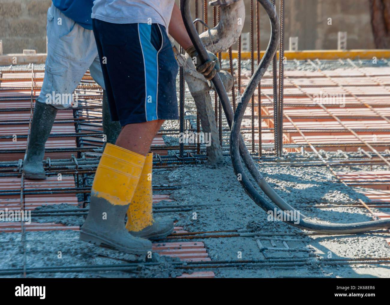 Building construction worker pouring cement or concrete with pump tube ...