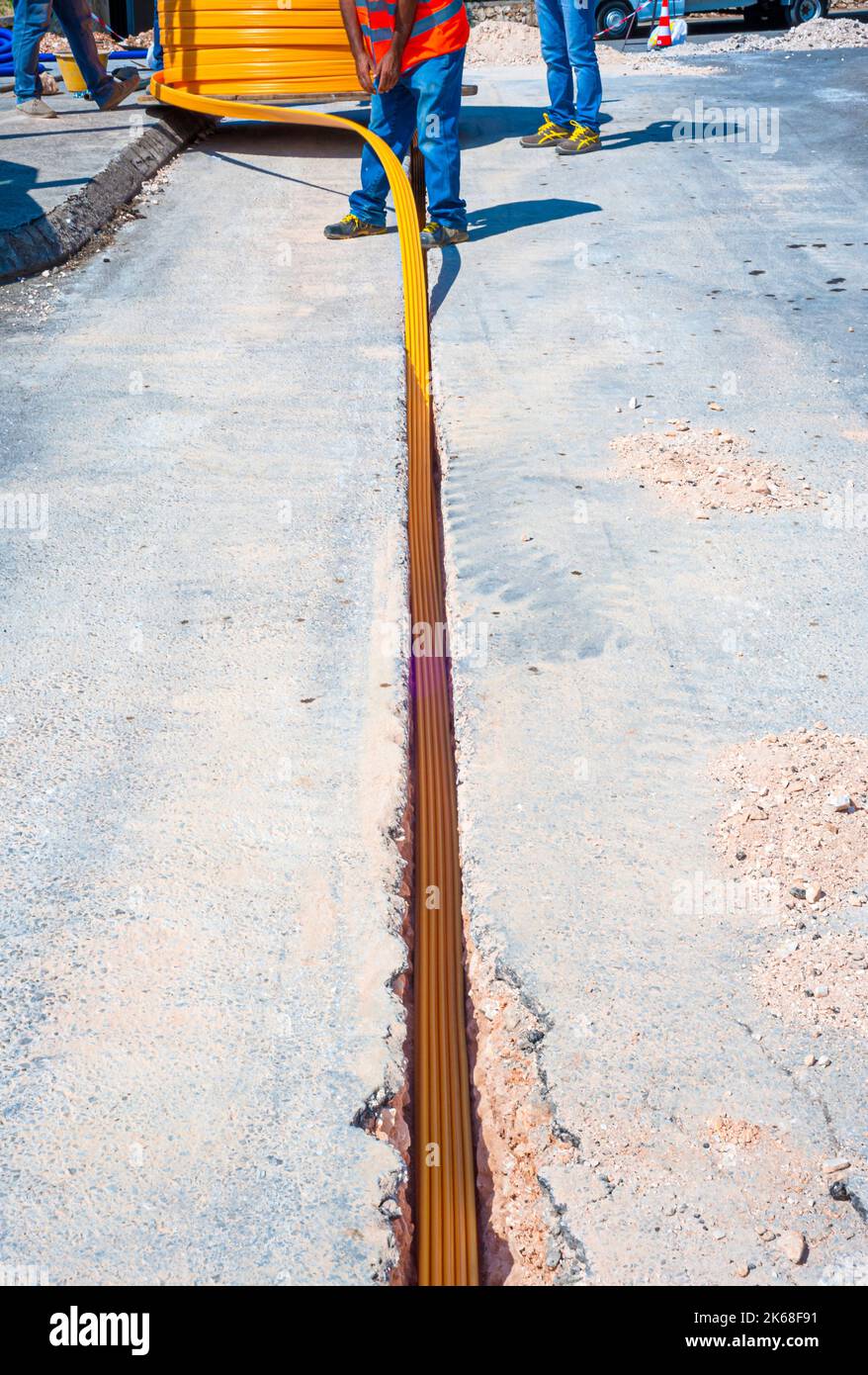 Worker inserts fiber optic cables buried in a micro trench Stock Photo ...