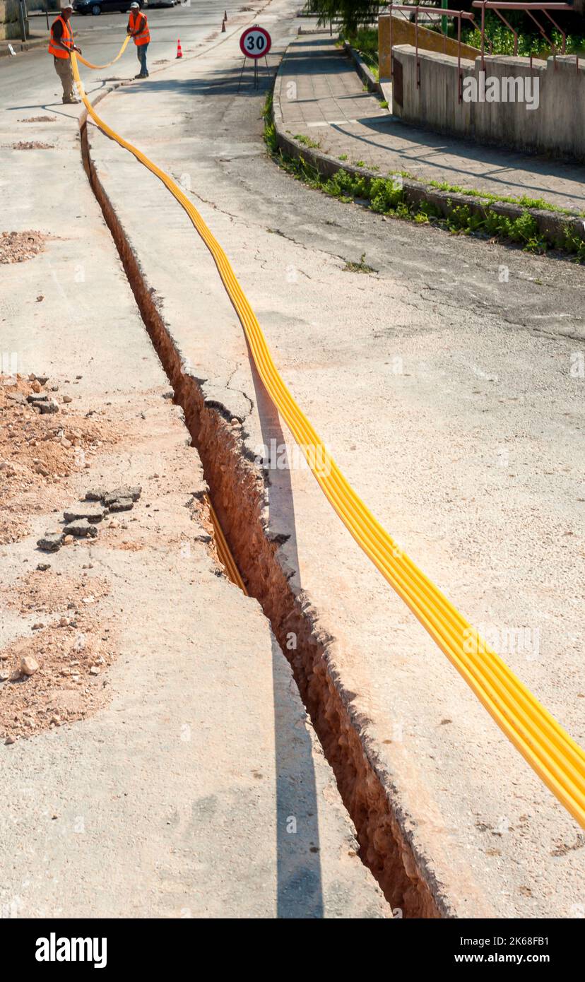 Worker inserts fiber optic cables buried in a micro trench Stock Photo ...