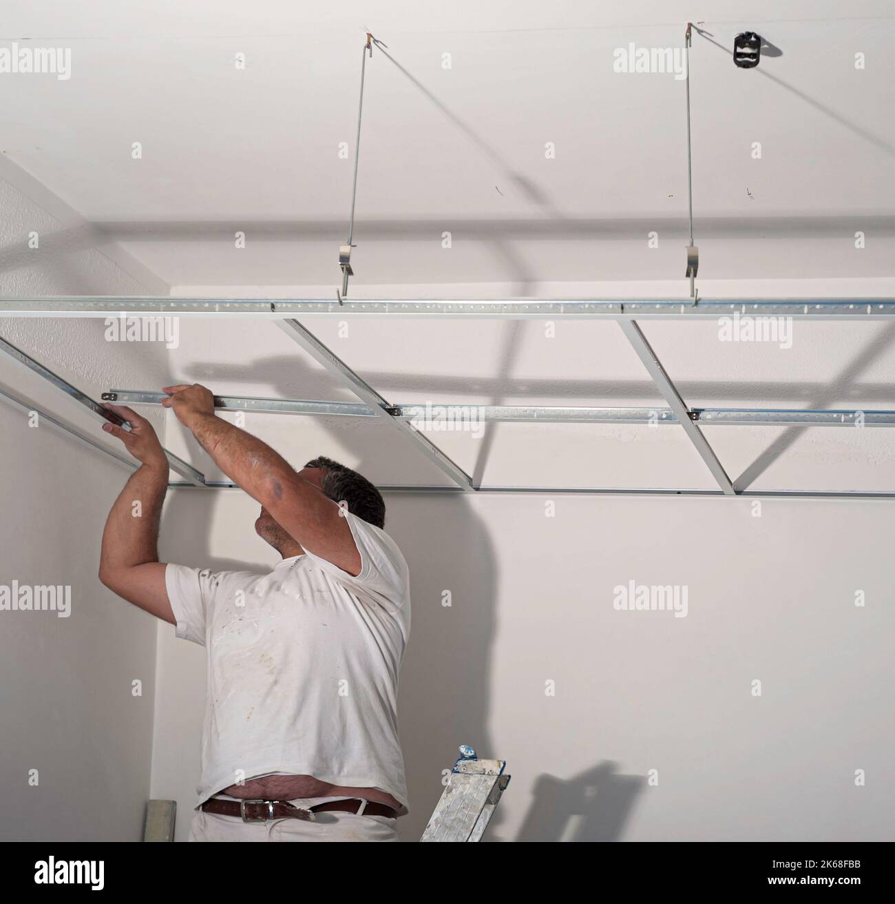 Construction worker assemble a suspended ceiling with drywall an. D ...
