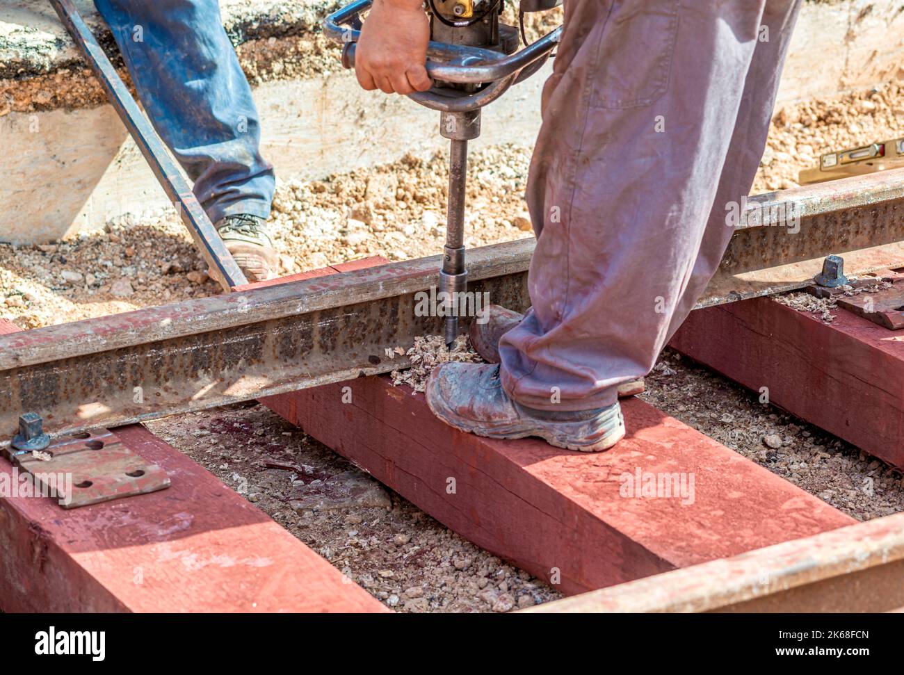 construction of railway track with wooden sleepers. Worker with a drill ...
