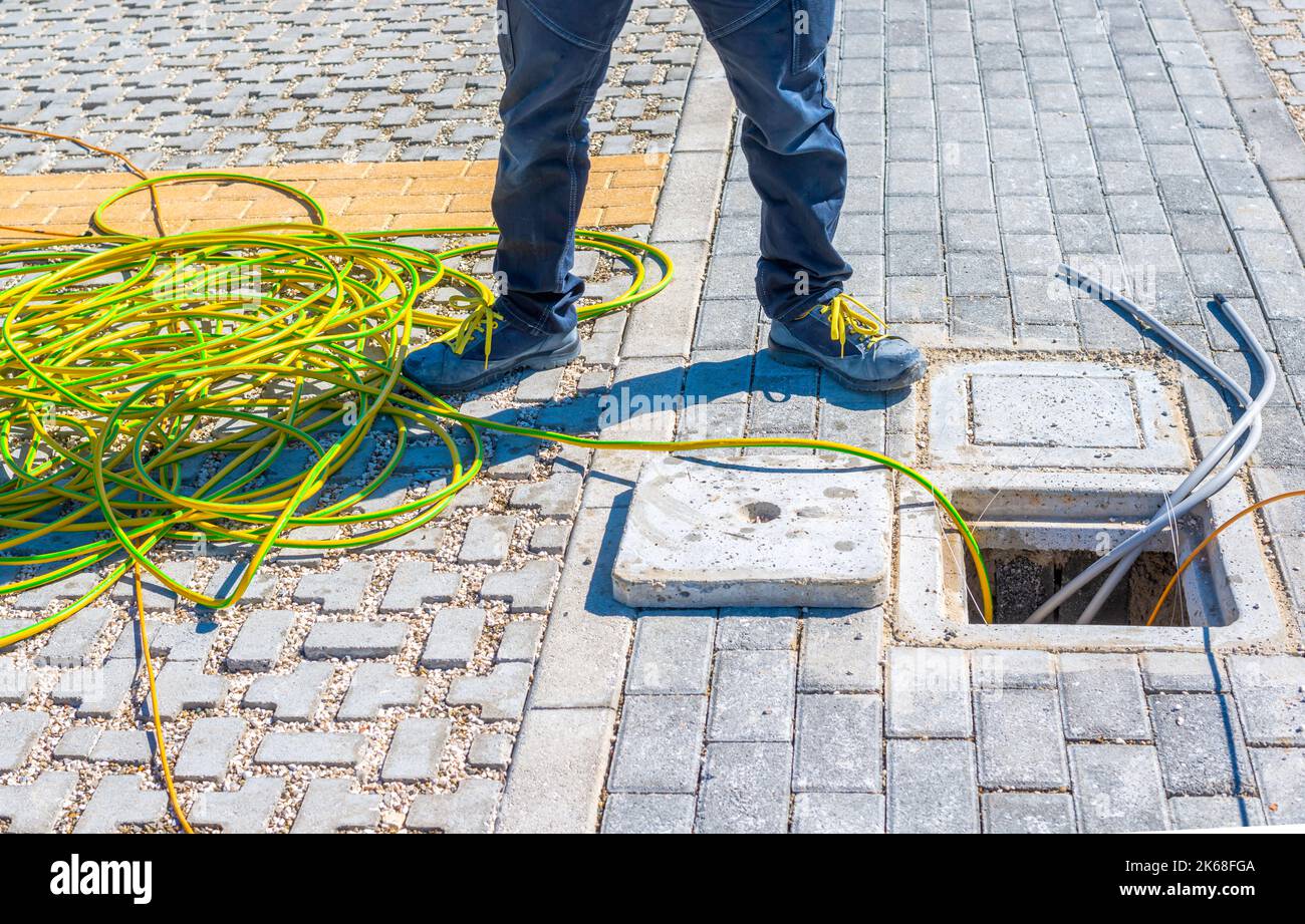 Worker places yellow-green electric vacs in a pit to complete an ...