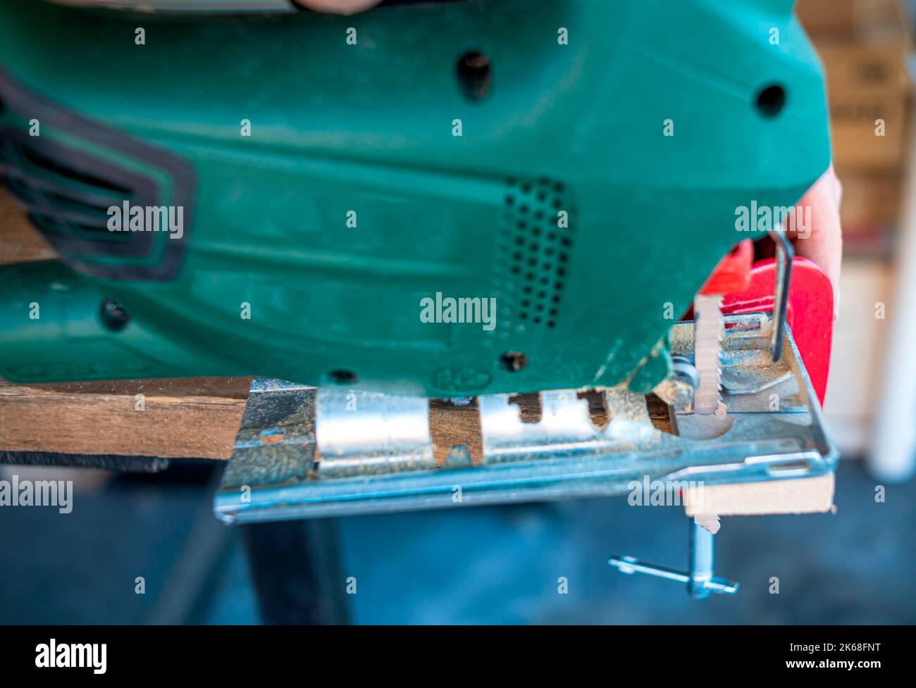 Sawdust flies off a metal blade as the jigsaw cuts into a workpiece ...