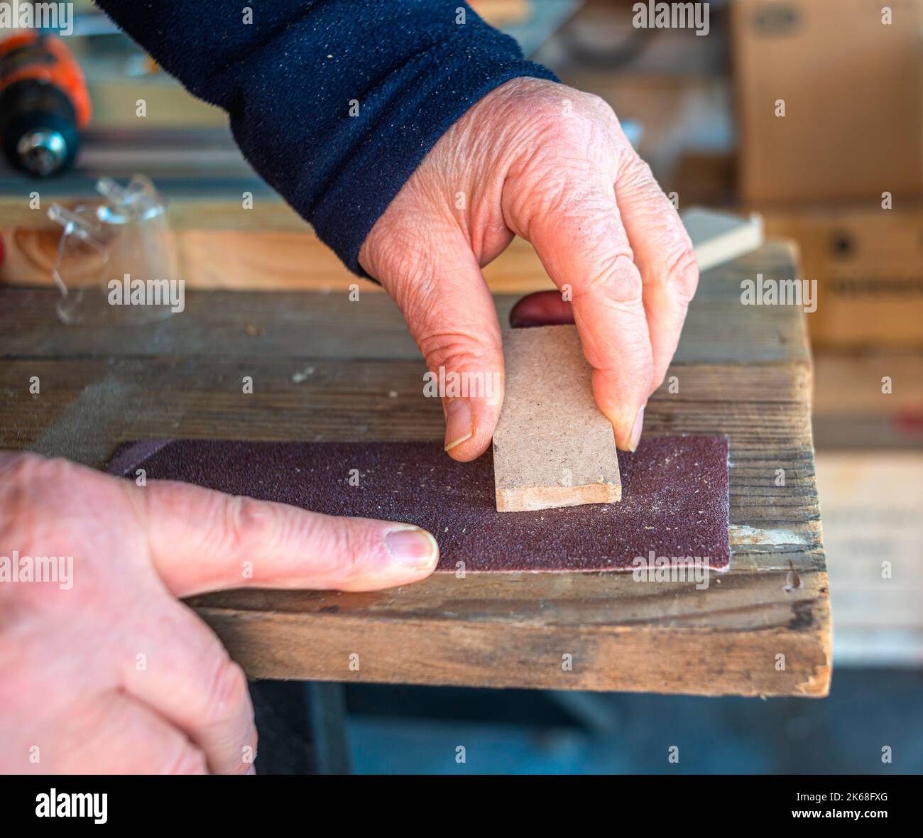 sanding wooden board using sand paper at workshop Stock Photo - Alamy