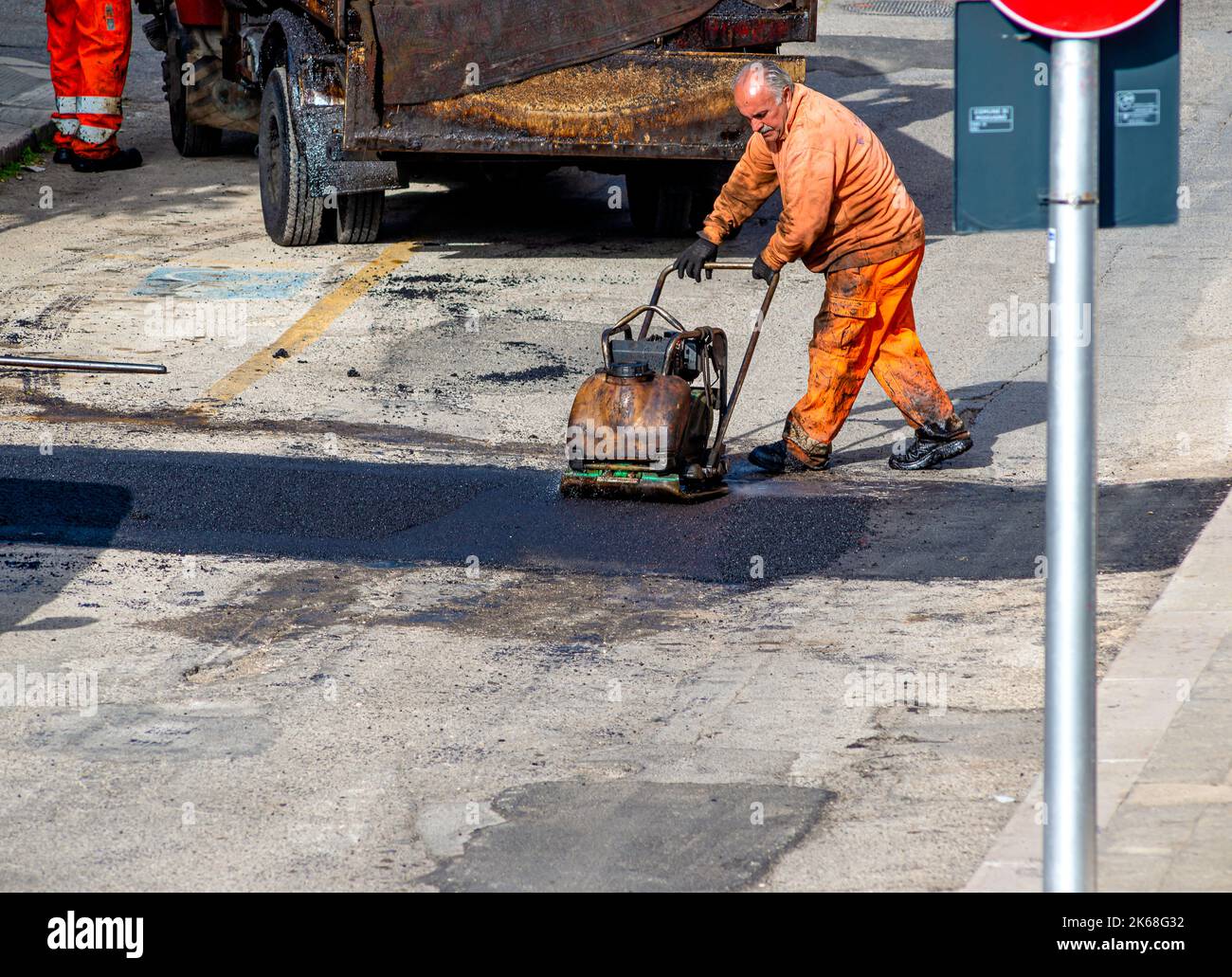 worker leveling fresh asphalt during asphalt pavement repair or ...