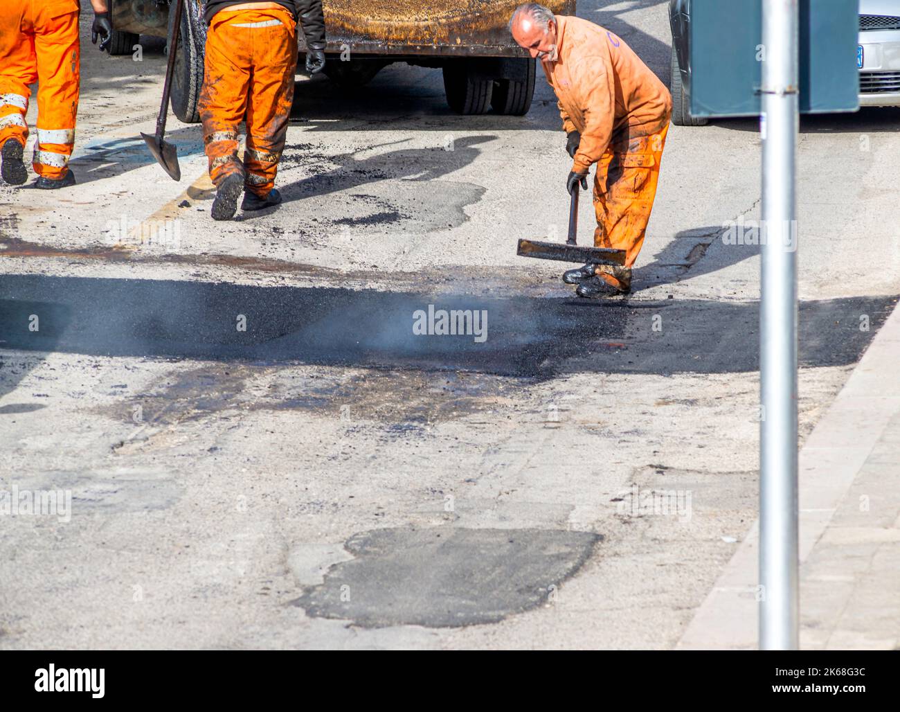worker leveling fresh asphalt during asphalt pavement repair or ...