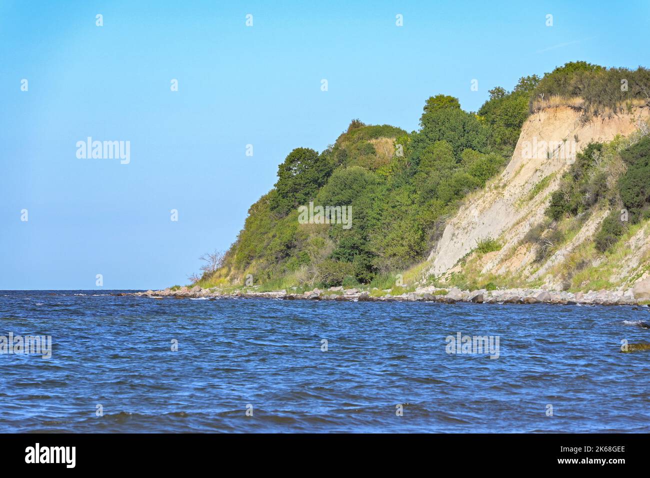 Steep coast with shrub vegetation and erosion of clay and boulders on ...