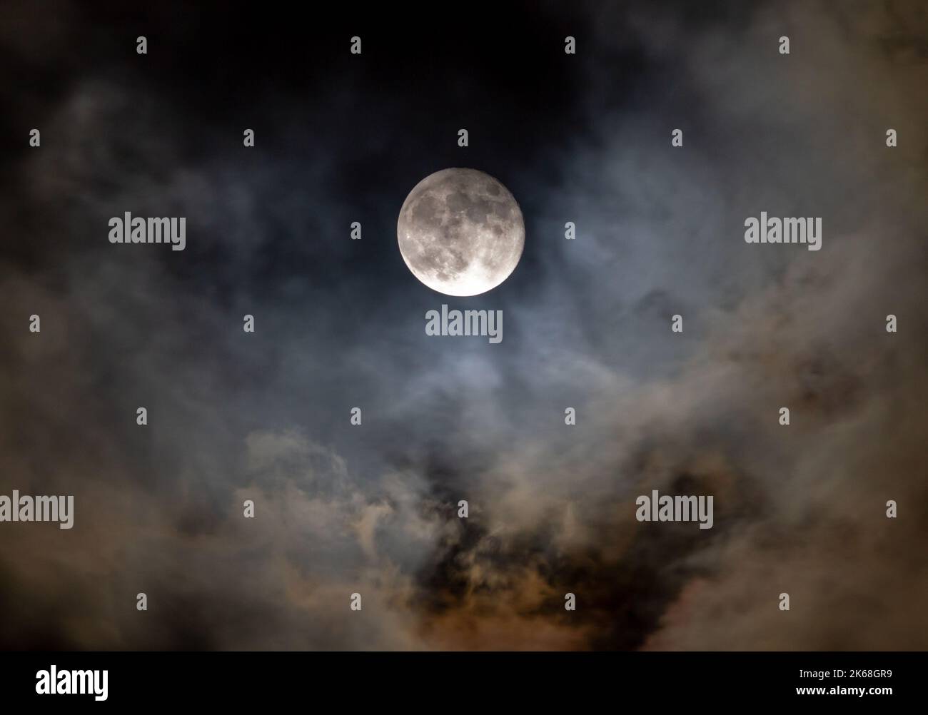 Colorful clouds pass in front of a full moon in the night sky Stock Photo - Alamy