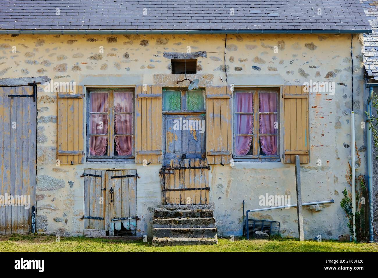 Neglected old country house with peeling shutters and door in a village ...