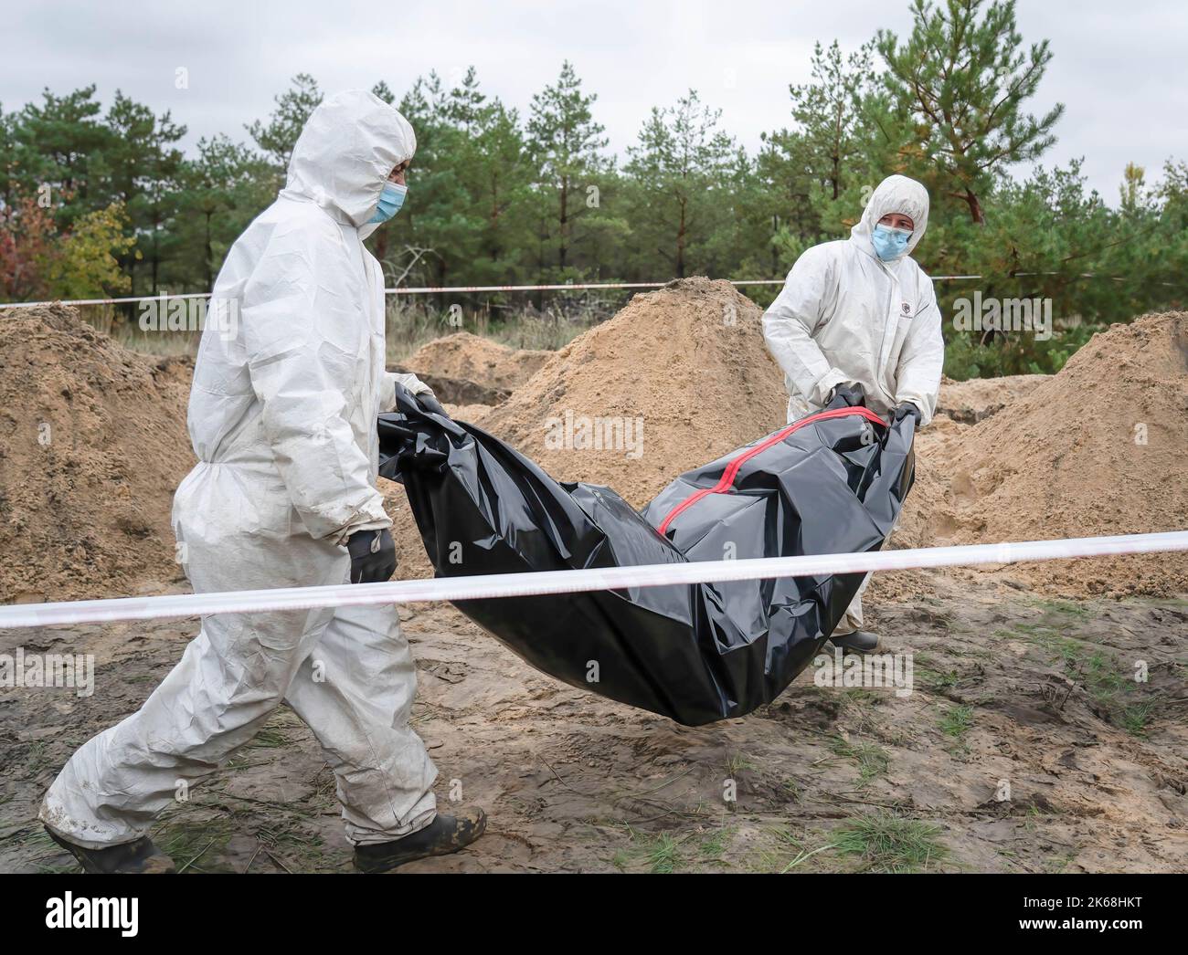 Investigators wearing protective gears are seen carrying a body bag ...
