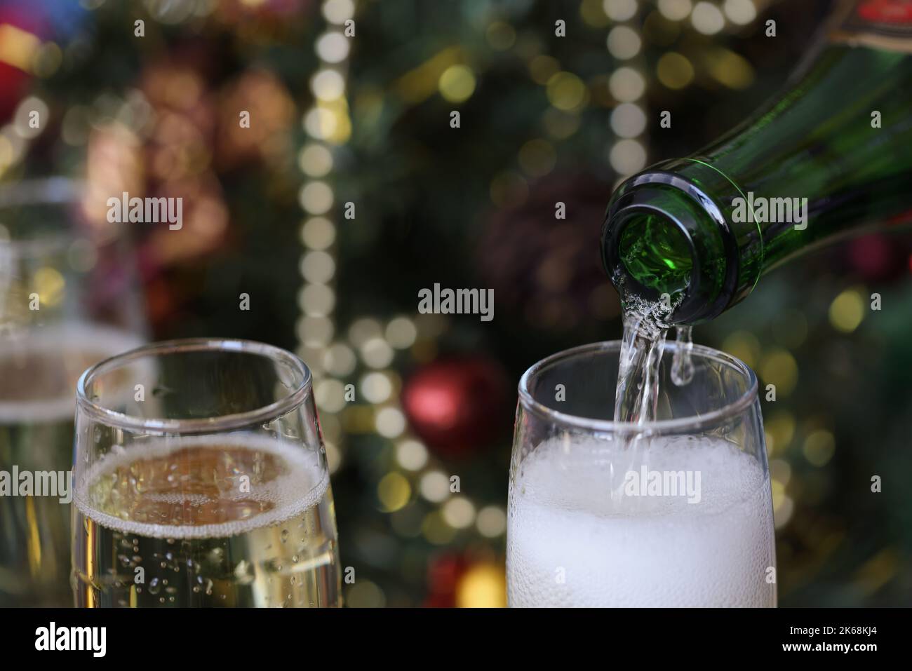 Someone pouring tasty champagne from bottle into glass for toast or ...