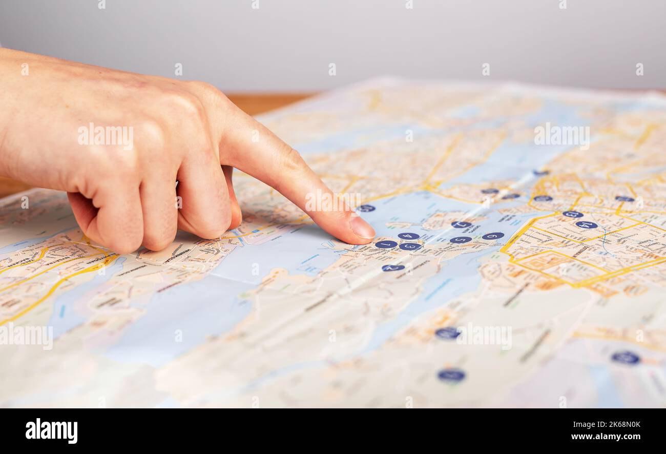 Finger pointing on location on paper map closeup. Abstract travel route ...