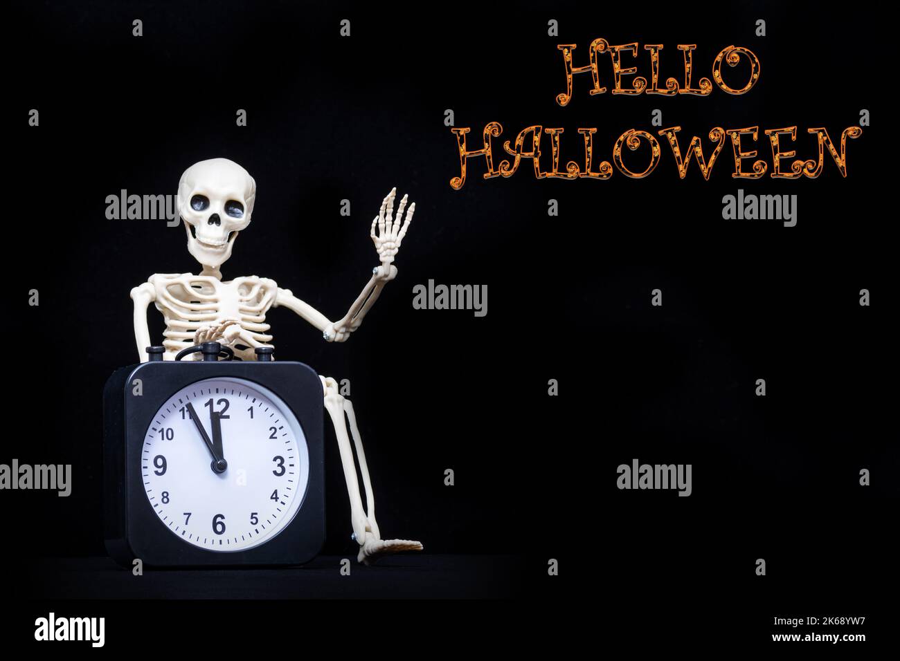 A human skeleton waving his hand, greeting holding an black alarm clock ...