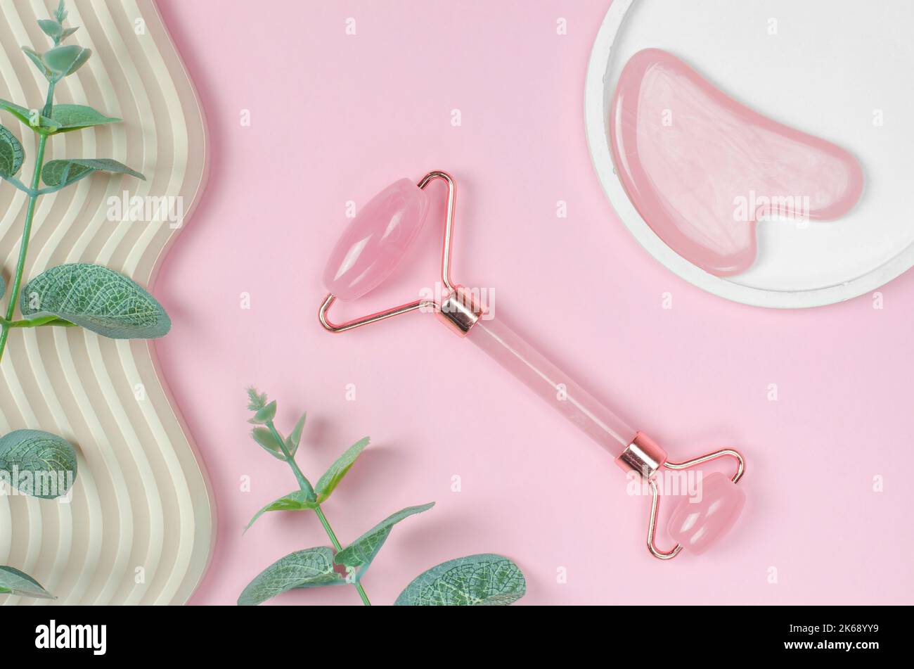 Roller jade facial massager on pink background with geometric shapes ...