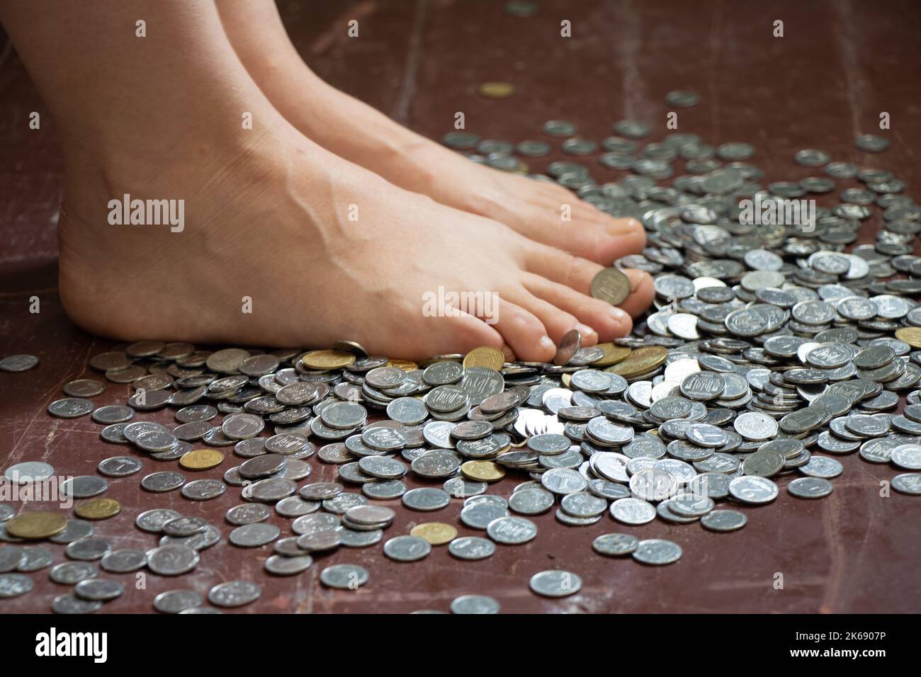 female feet stand on Ukrainian small coins on the floor of the house ...