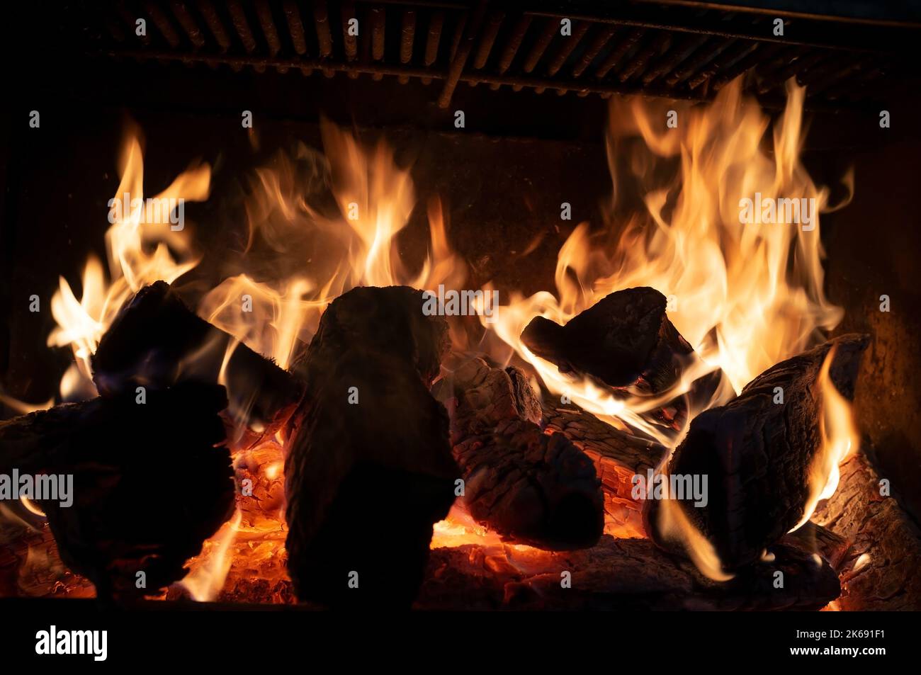 Fire and burning firewood in an iron fireplace to heat a house during ...