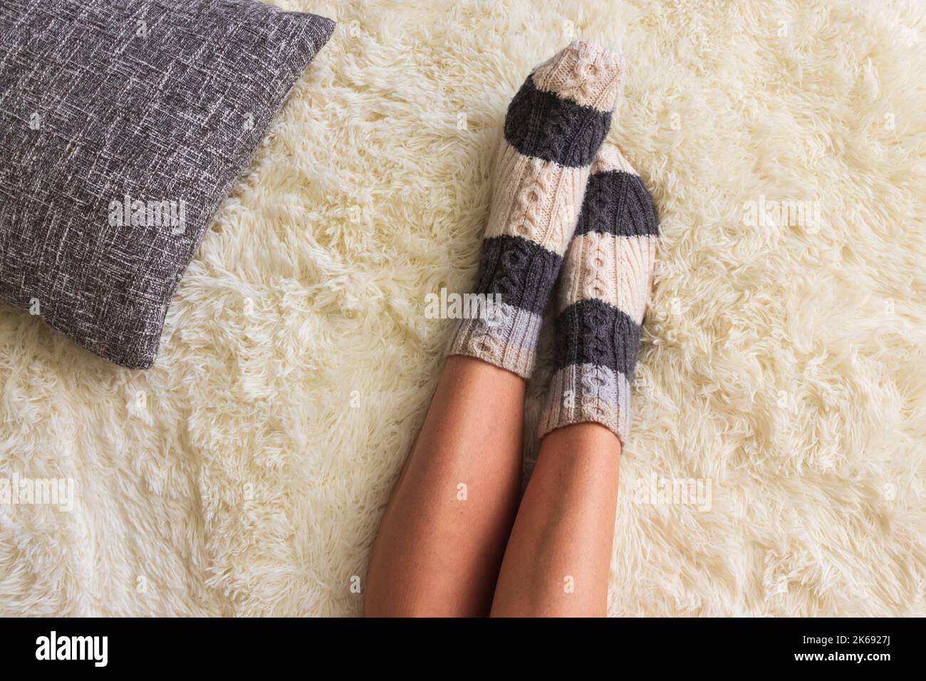 Girl in warm woolen socks with pillow, top view. Woman on white blanket ...