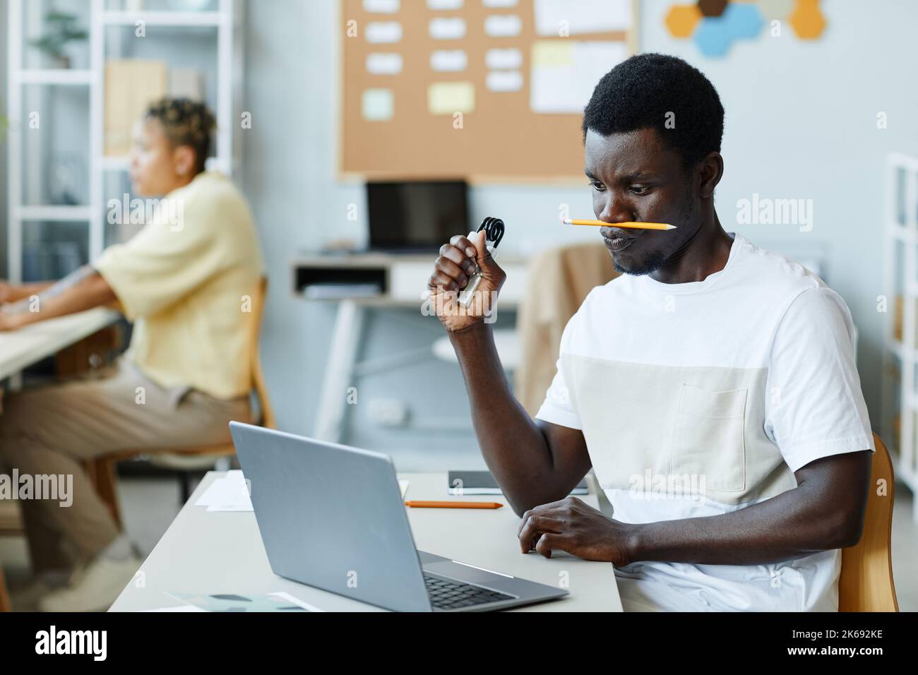 Portrait of young black man using multiple objects as fidget toys while ...
