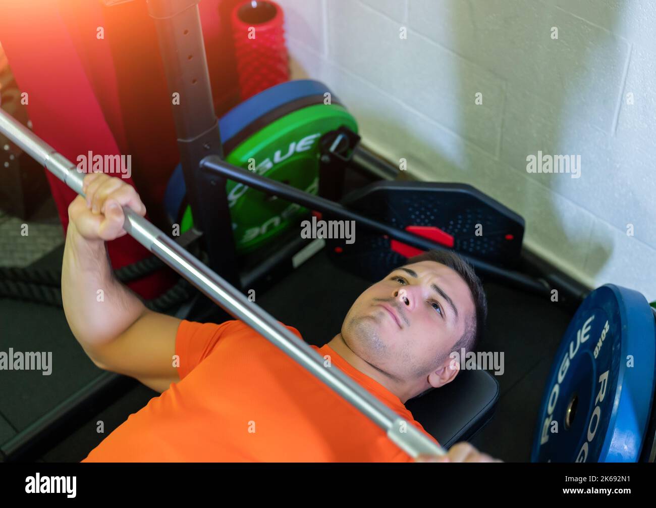 Amazing image of a young man doing bench press with a maximum weight ...