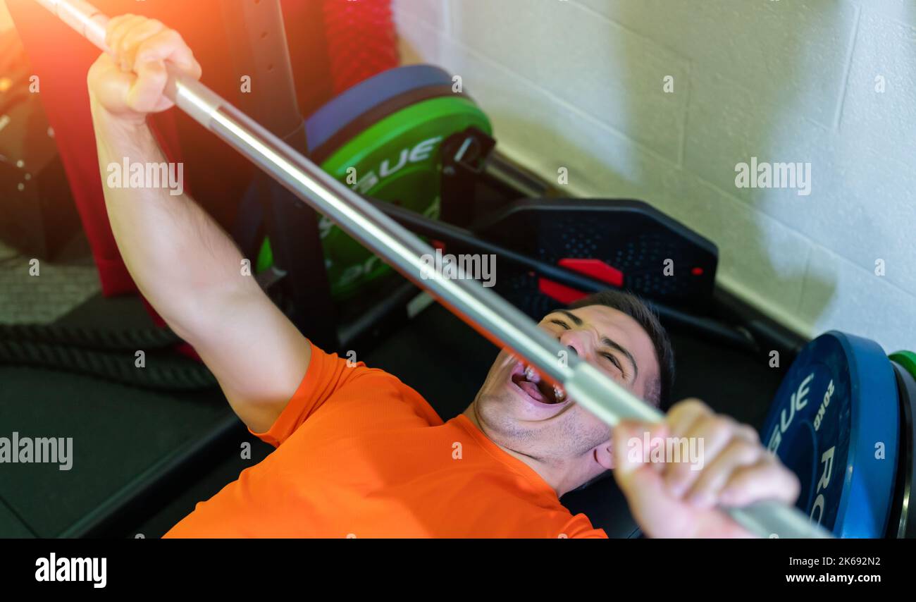 Amazing image of a young man doing bench press with a maximum weight ...