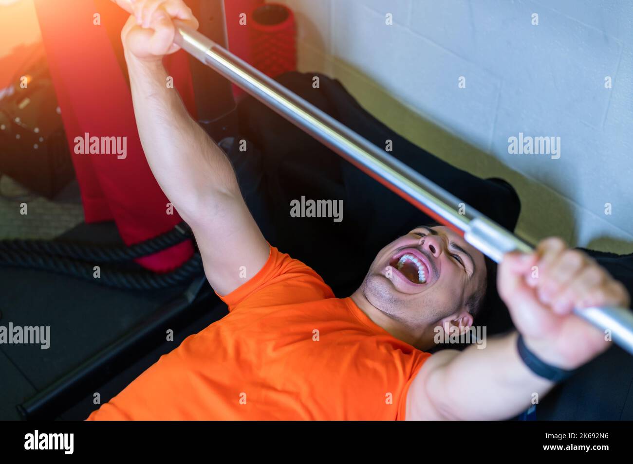 Amazing image of a young man doing bench press with a maximum weight ...