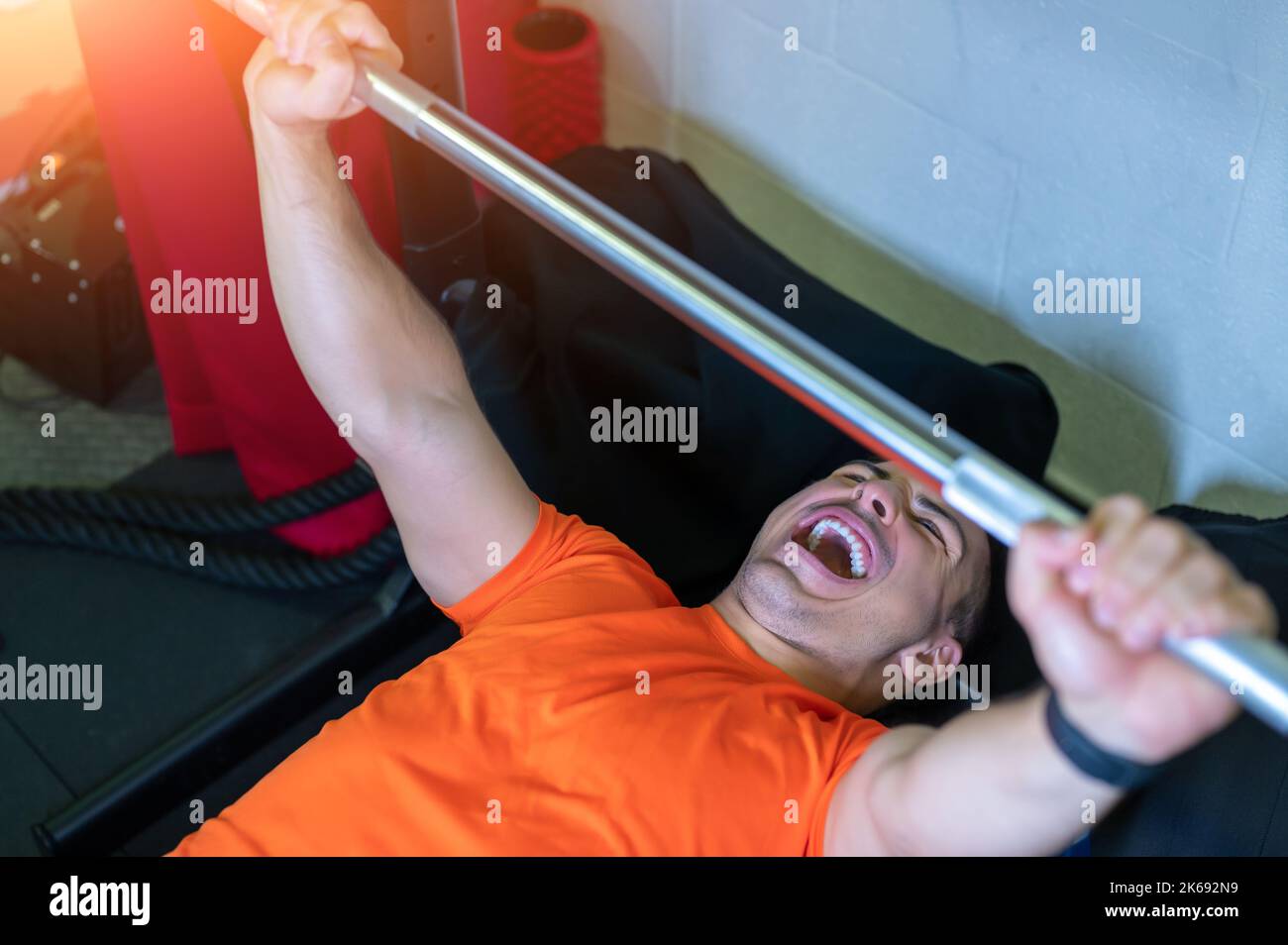 Amazing image of a young man doing bench press with a maximum weight ...