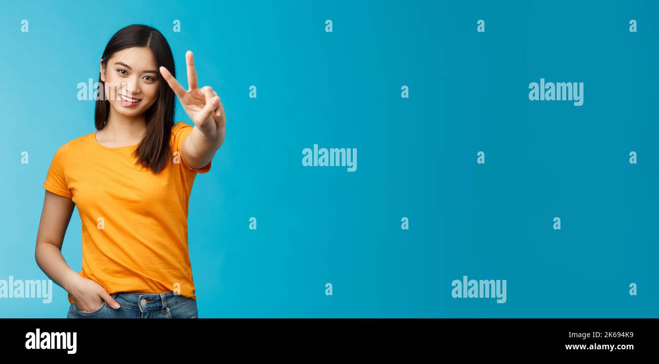 Cheerful friendly asian girl pacifist smiling happily show peace ...
