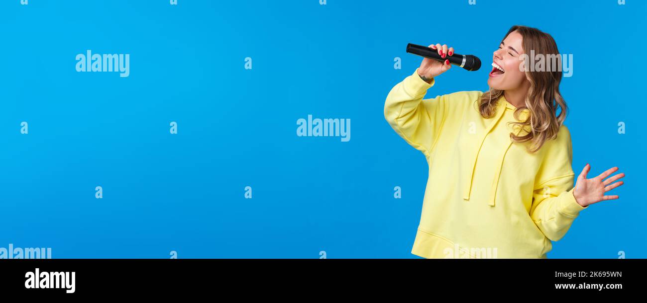 Carefree happy blond european girl having fun, enjoy singing karaoke ...