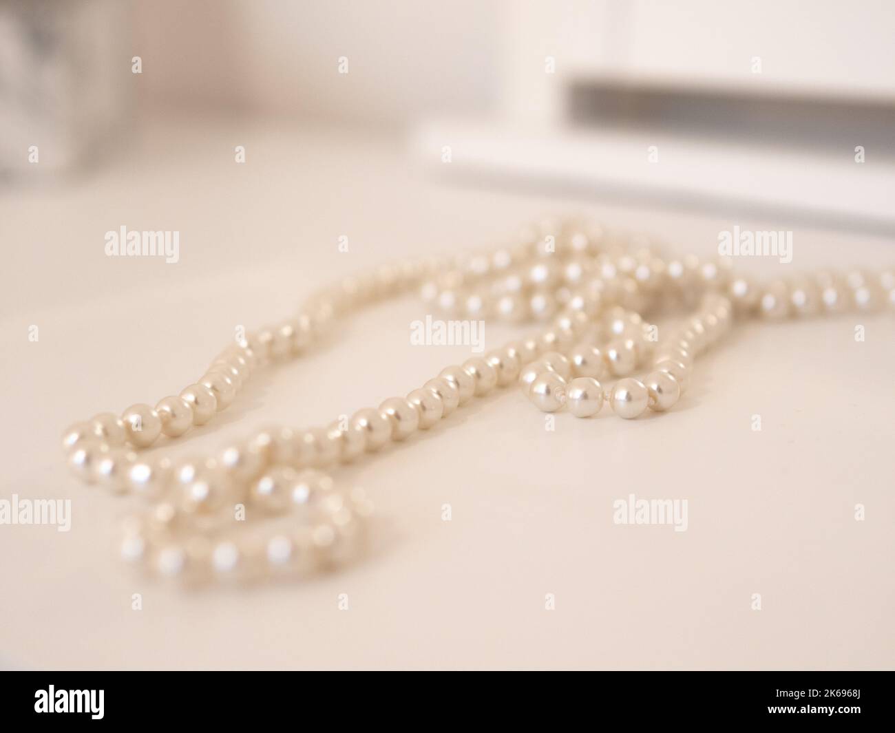 A selective focus shot of a beautiful shiny pearl necklace on a white ...