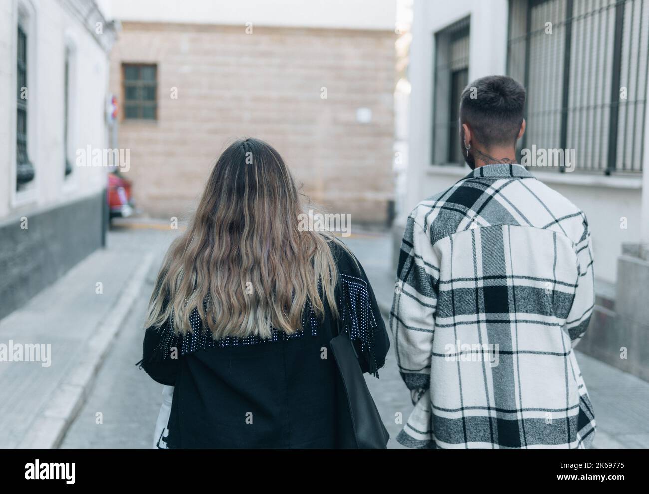 A shallow focus of the back view of a couple walking away in an alley ...