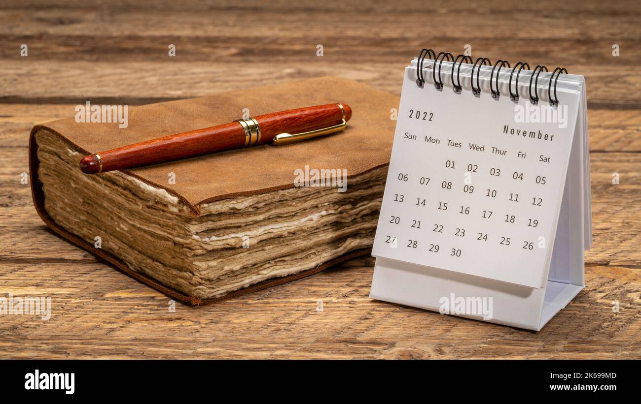 November 2022 - small spiral desktop calendar against rustic wood with ...