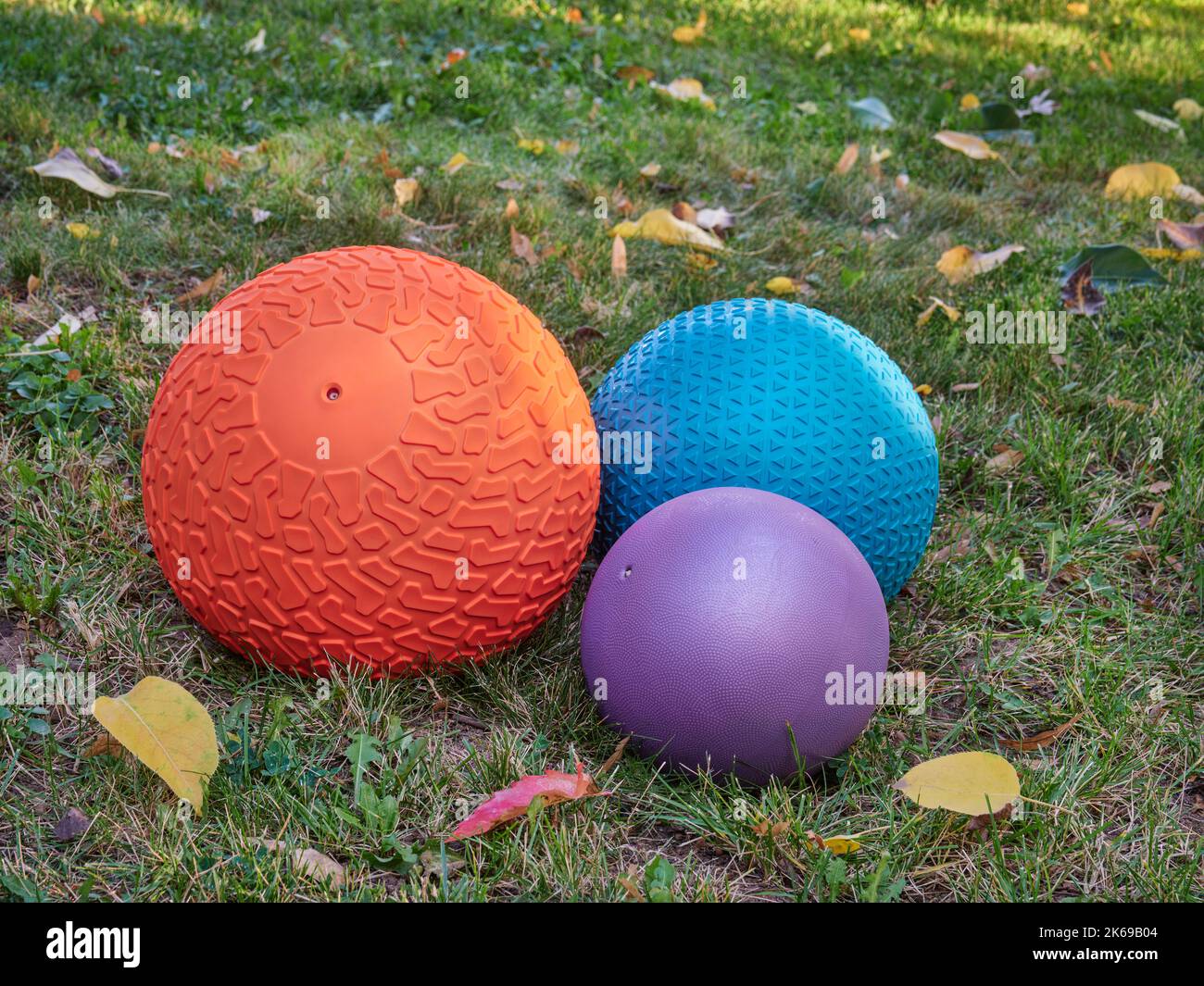 three heavy slam balls filled with sand in a backyard lawn, exercise ...