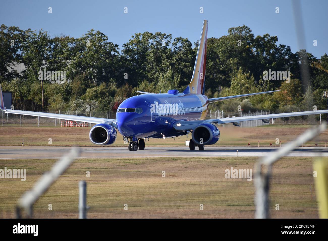 A blue aircraft with yellow and red empennage lining up on the runway ...