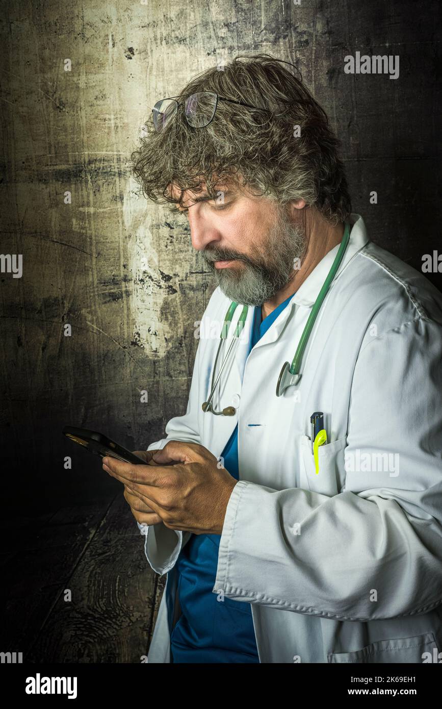 bearded mature doctor dressed in a blue surgical suit and a white coat ...