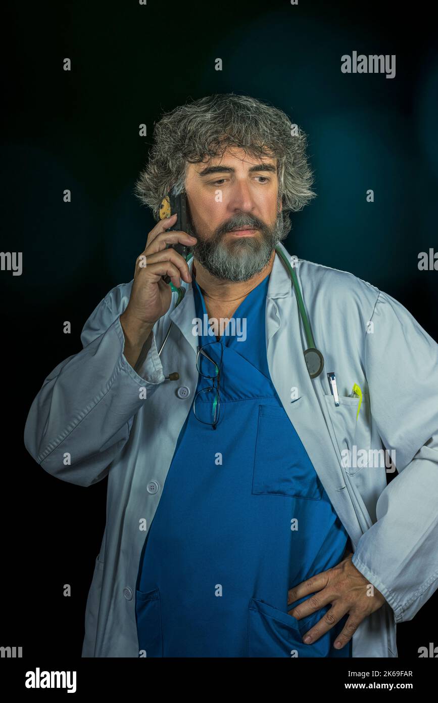 mature doctor with a beard dressed in a blue surgical suit and a white ...