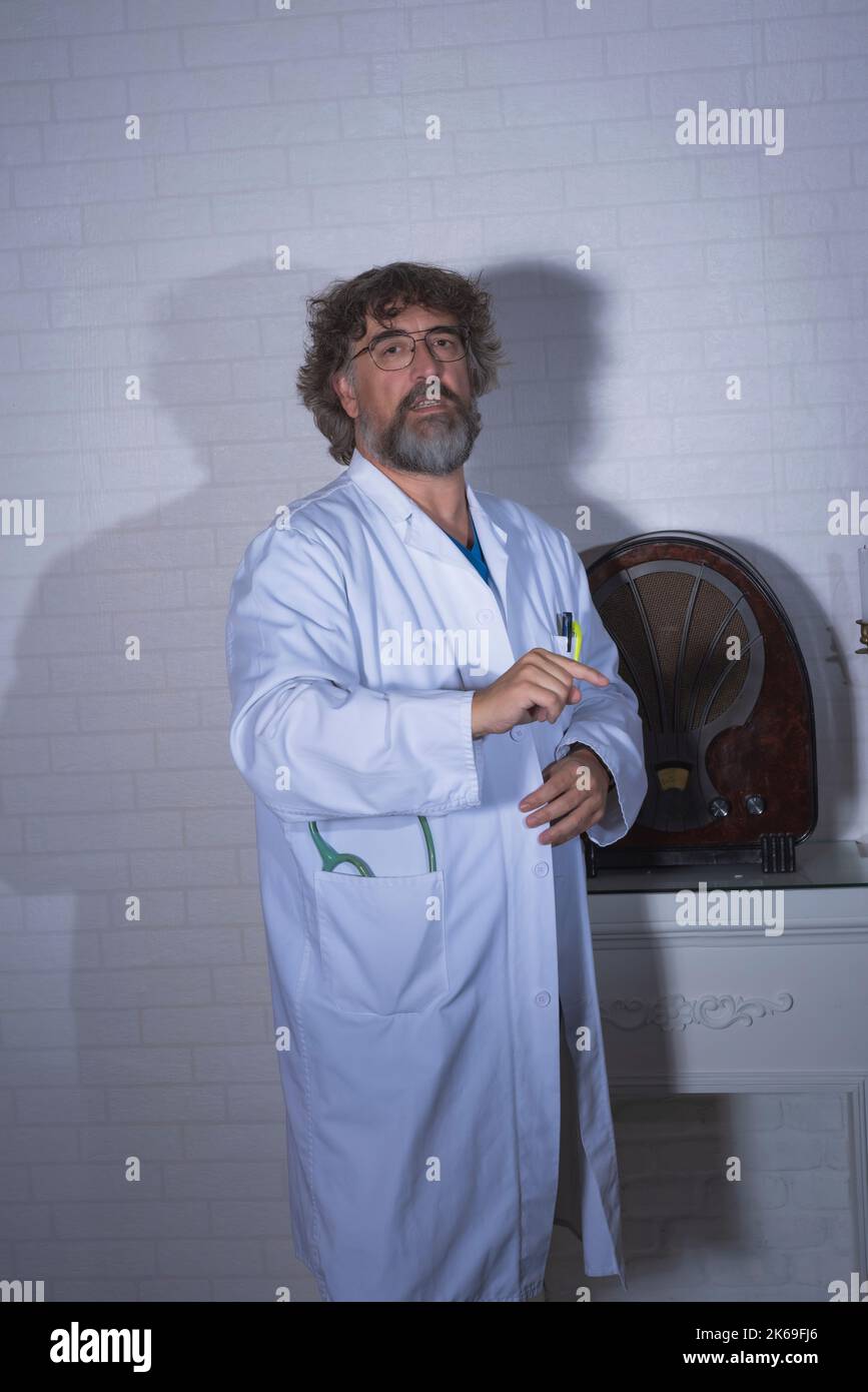 bearded doctor dressed in a blue operating room clothes and white coat ...