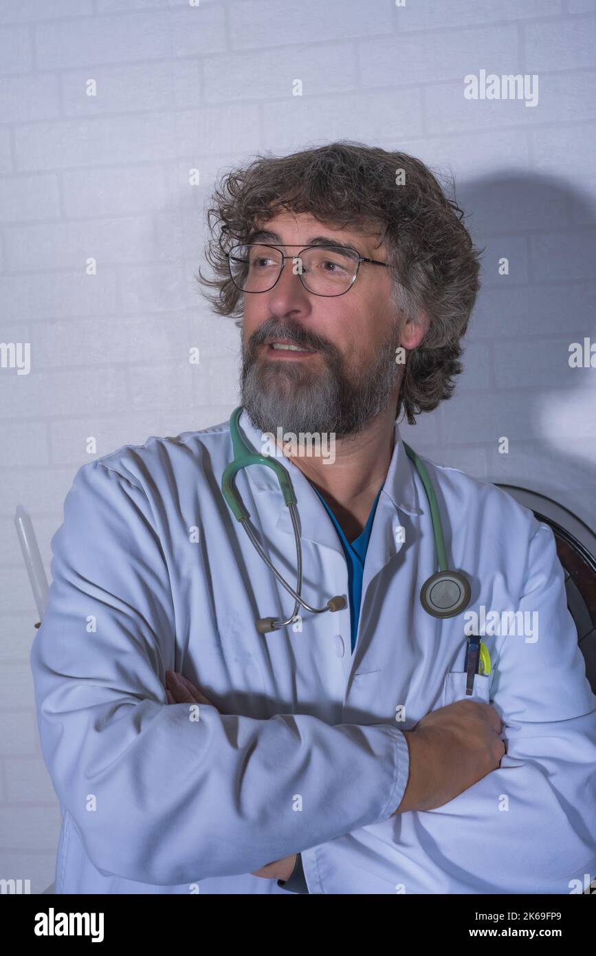 bearded doctor dressed in a blue operating room clothes and white coat ...